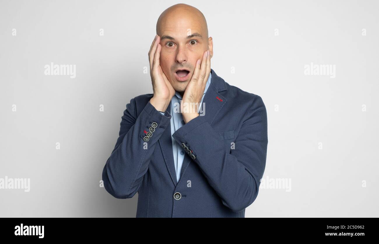Shocked bald man looking at camera. Isolated over grey studio wall ...