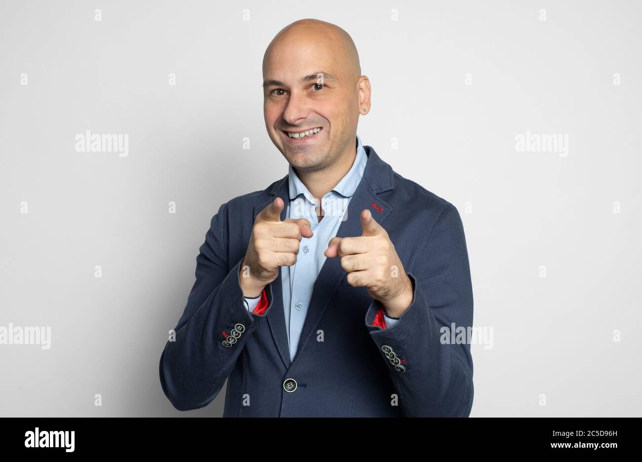 Smiling bald man pointing his fingers at you. Isolated over grey studio ...