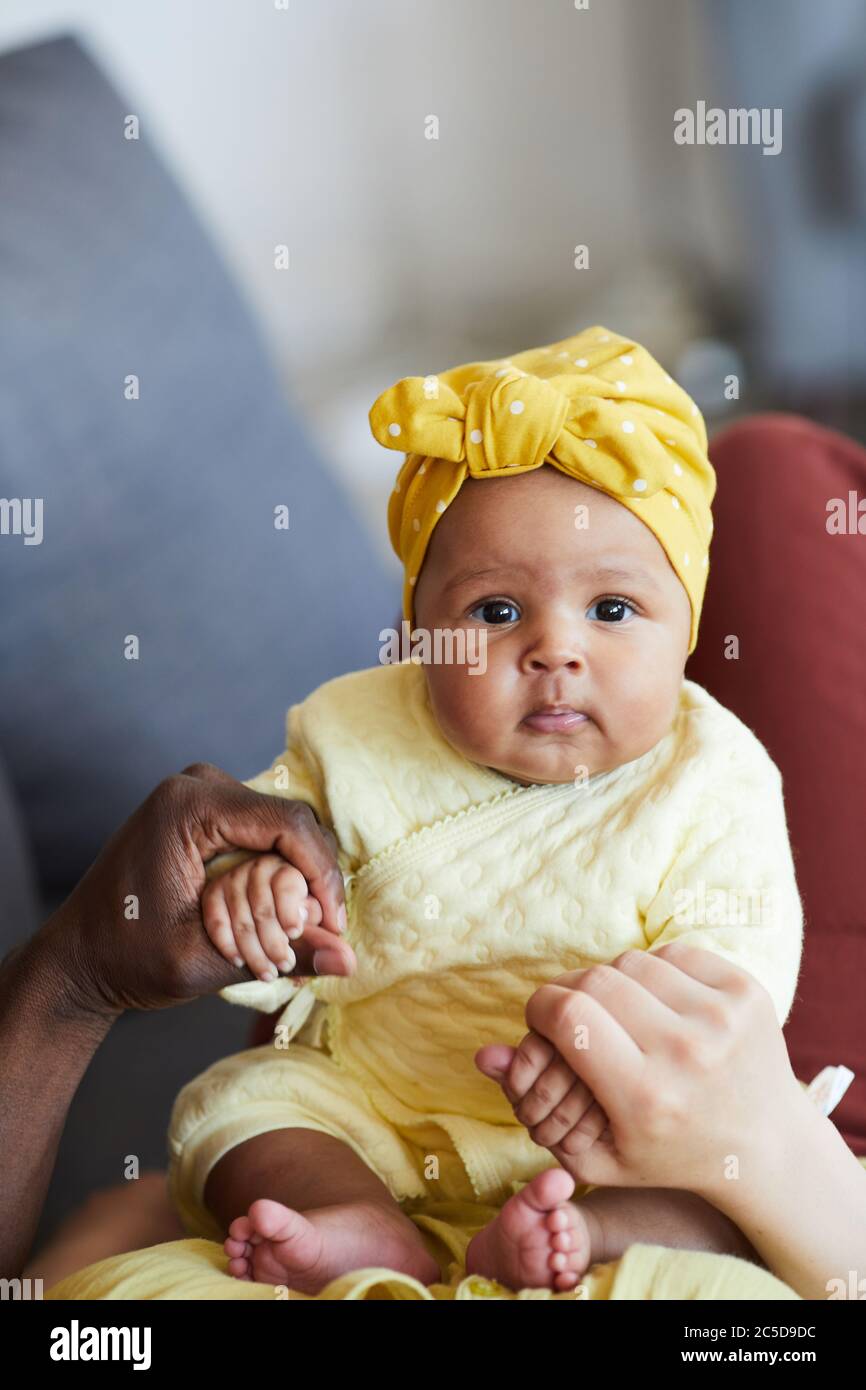 Portrait of cute baby girl looking at camera and playing with her ...