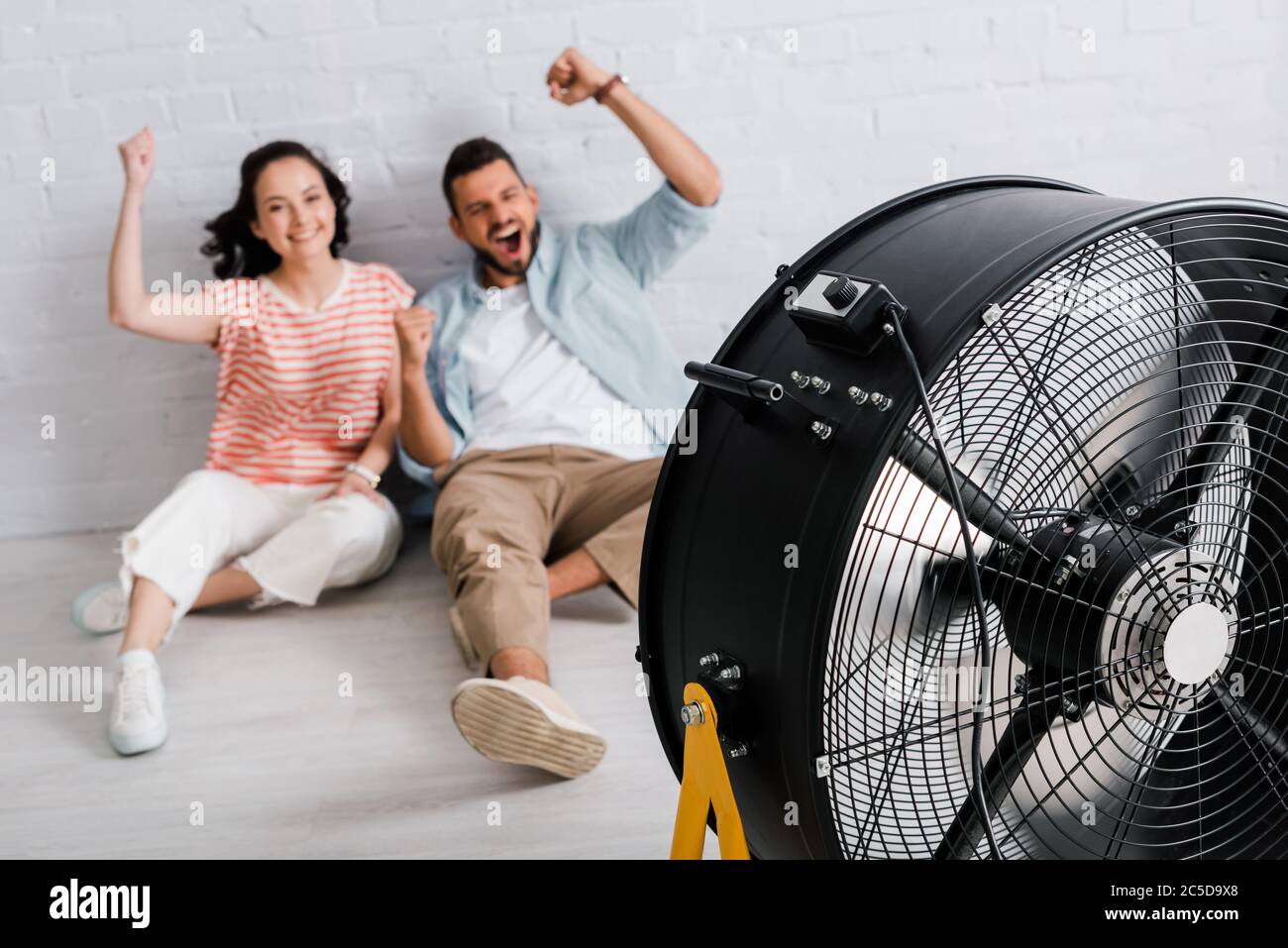Selective focus of cheerful couple showing yeah gesture while sitting ...