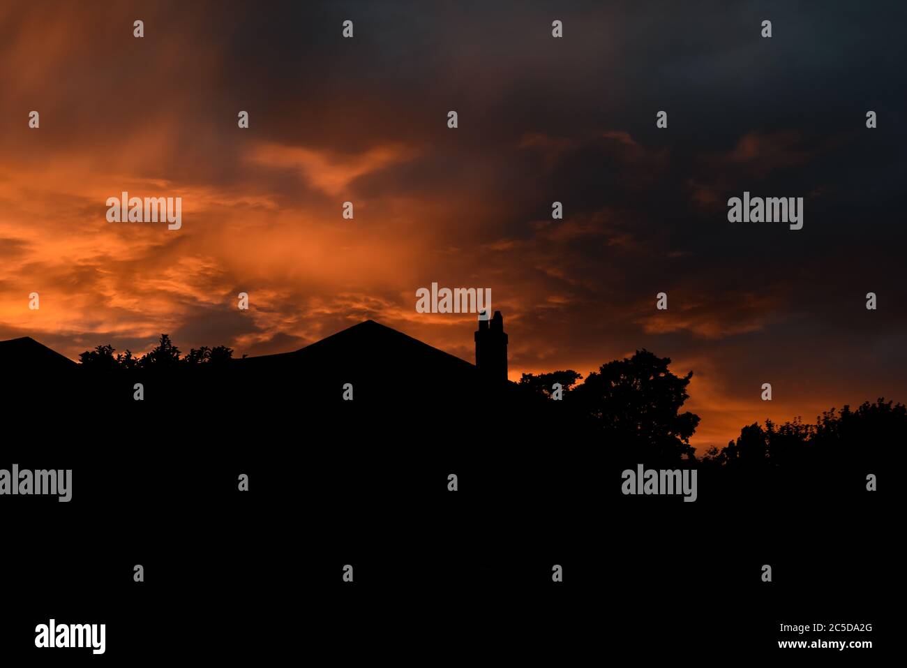 Silhouette of street of houses exterior in sunset with dark sky behind ...