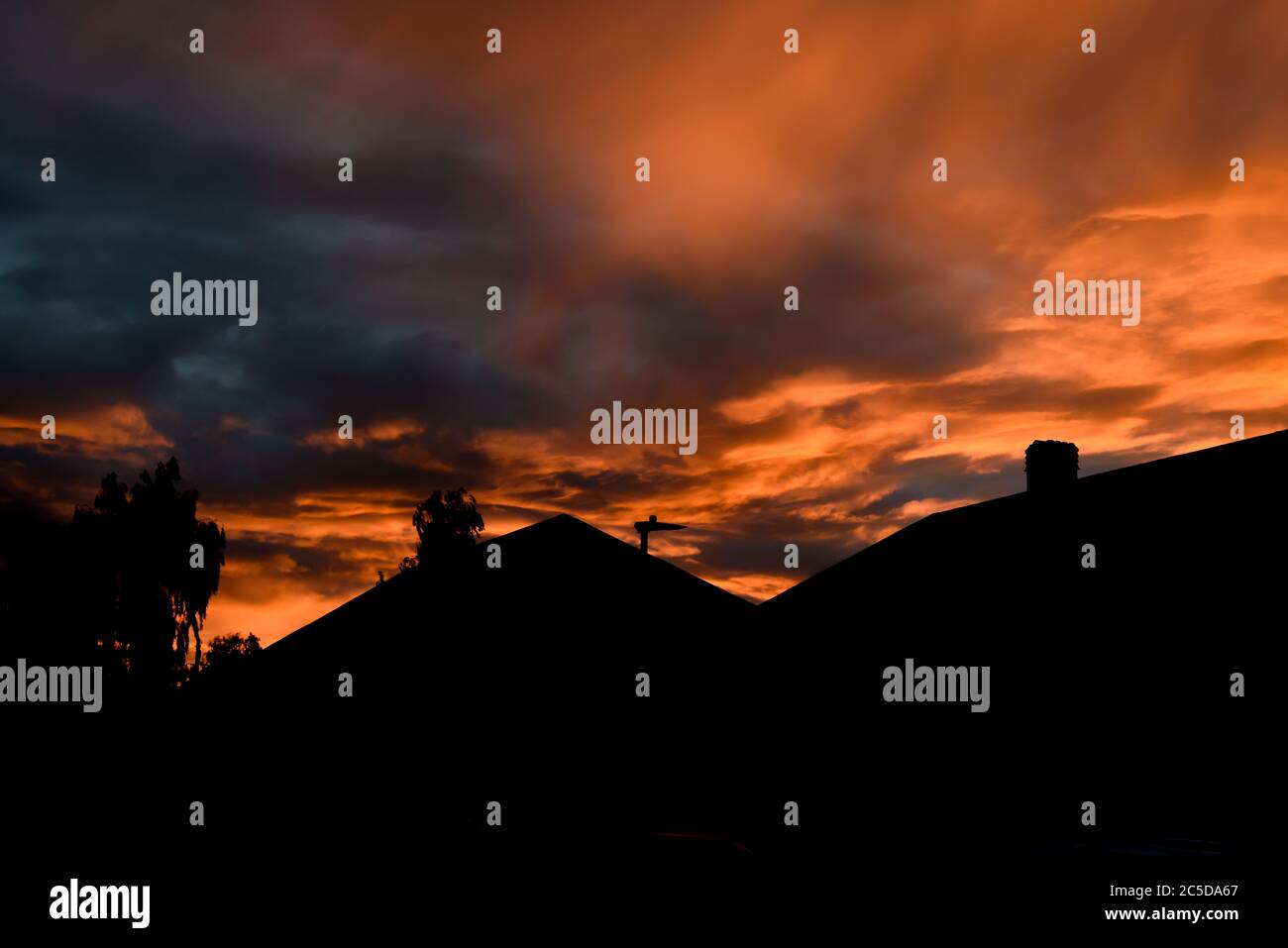 Silhouette of street of houses exterior in sunset with dark sky behind ...