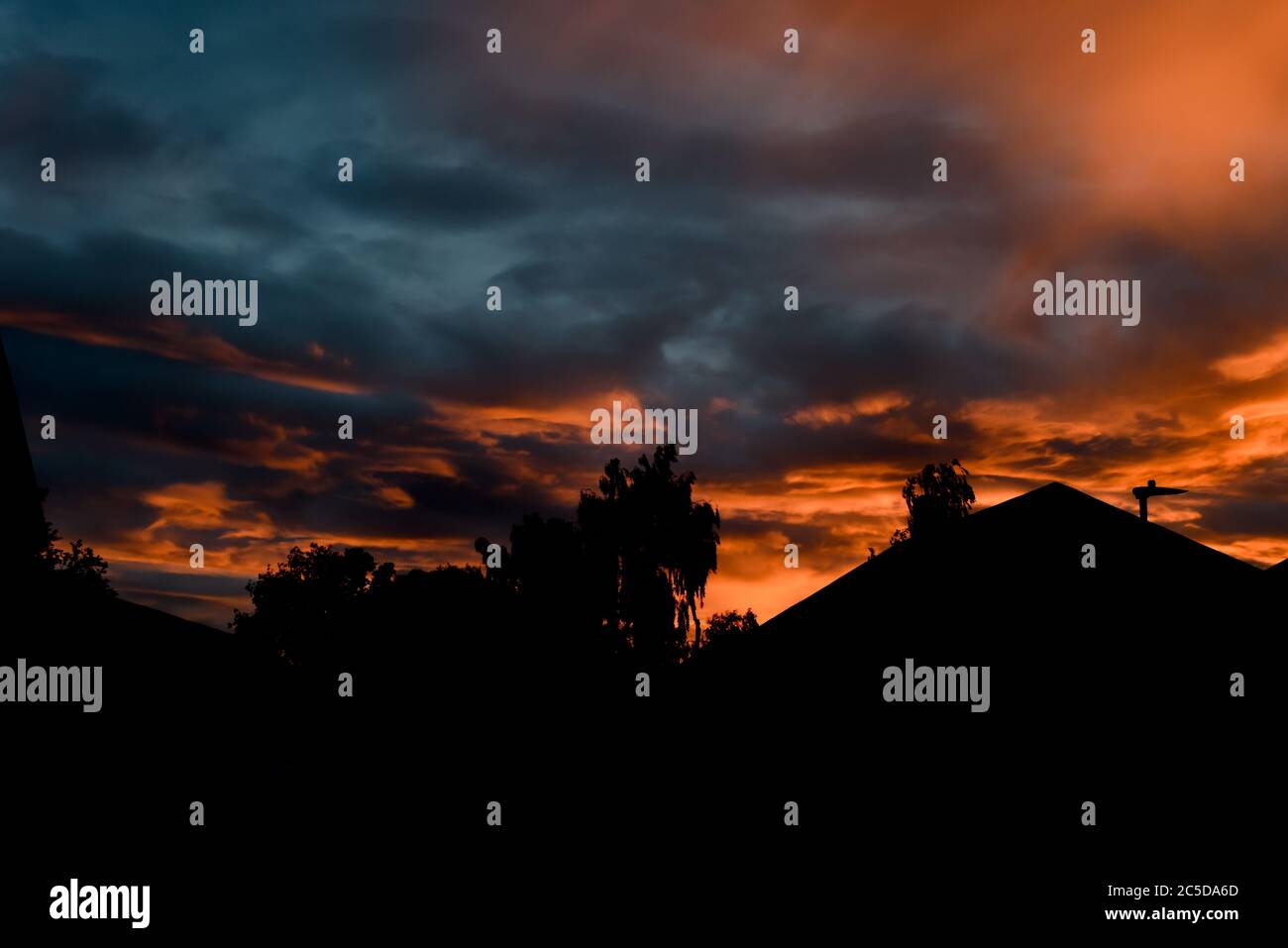 Silhouette of street of houses exterior in sunset with dark sky behind ...