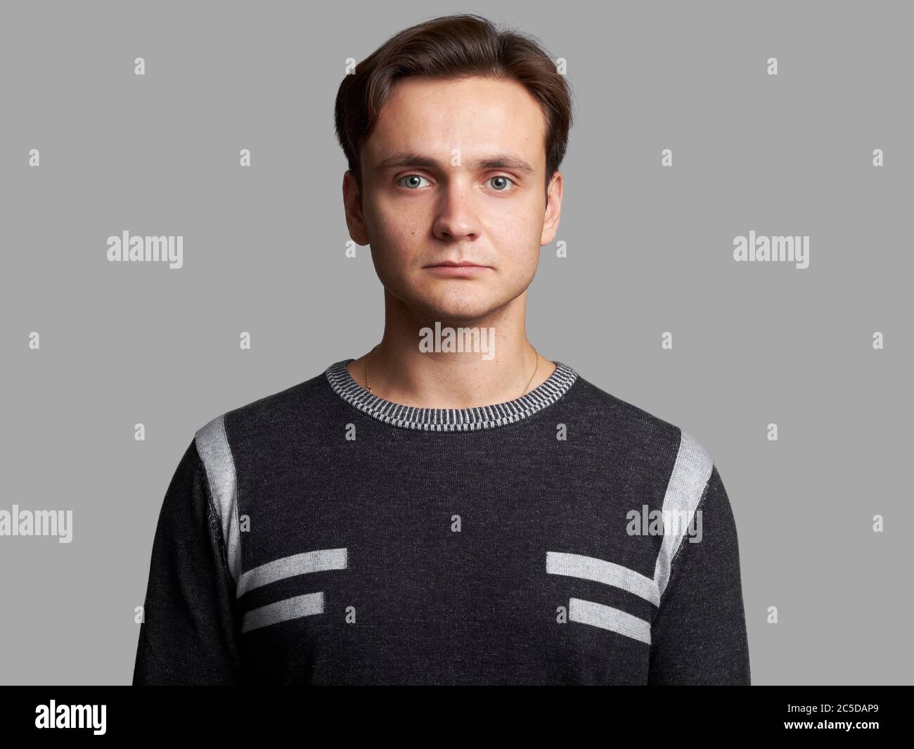 Handsome man looking at camera isolated on a studio gray background ...
