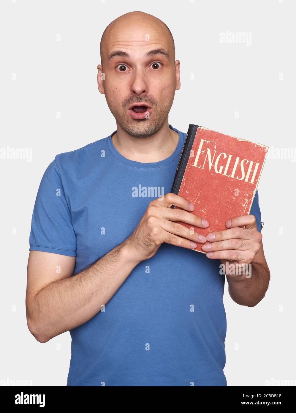 Shocked bald man holds an English textbook. Isolated on grey background ...