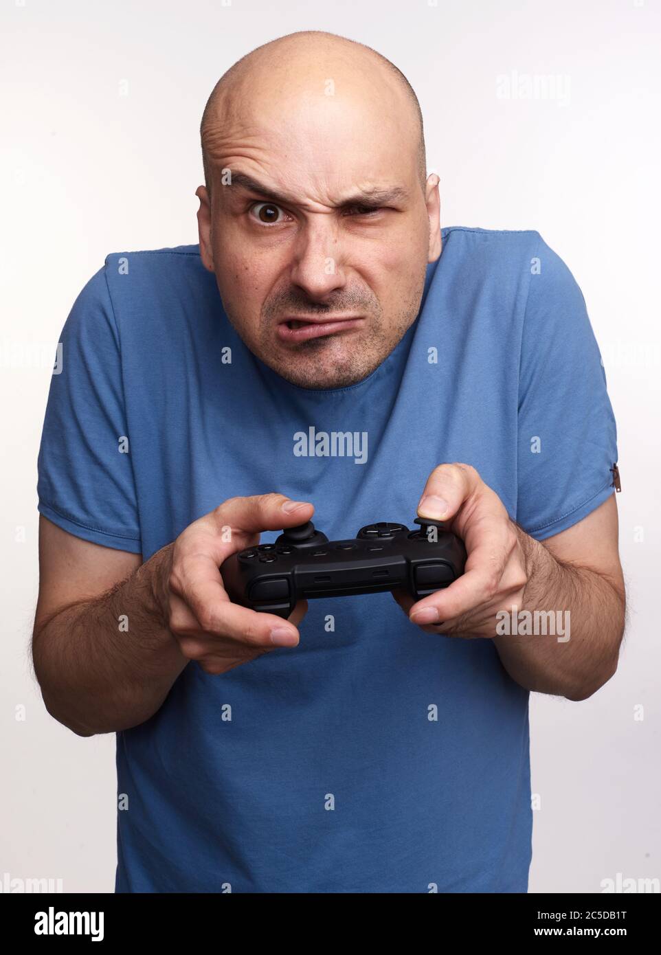 Angry bald man plays computer game isolated on grey studio background ...