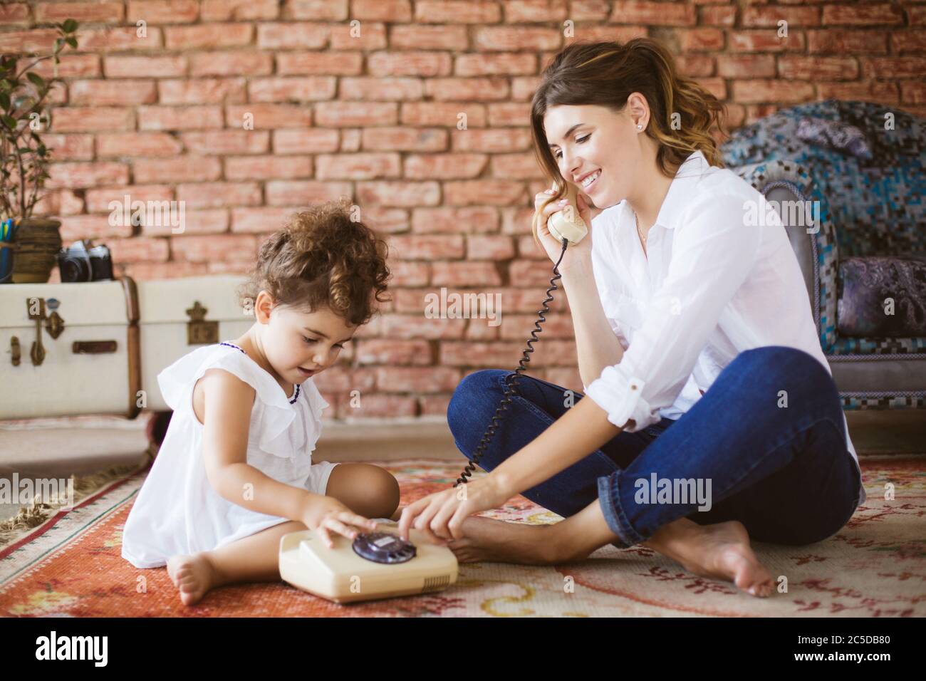 Young smiling mother and little pretty daughter dreamily playing Stock ...