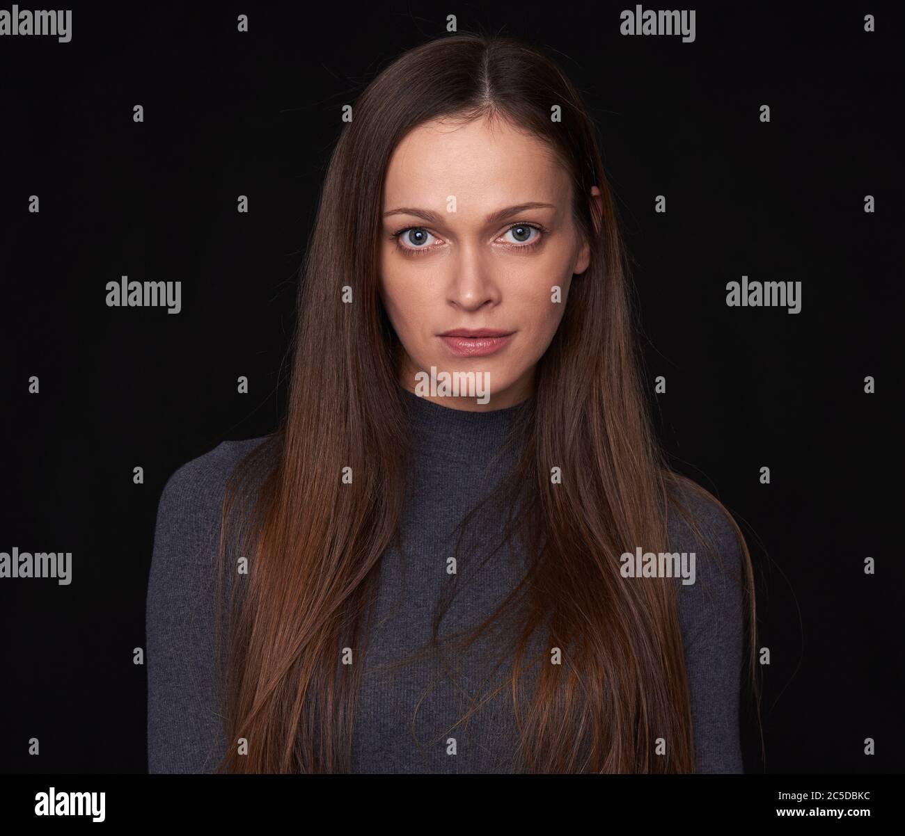 portrait of a pretty woman with long brown hair over black studio ...