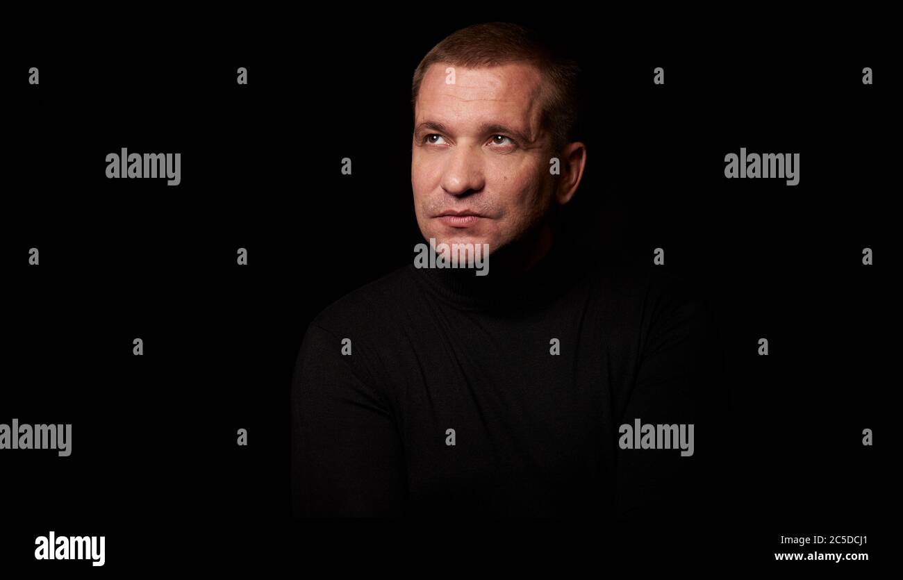 Serious man looking up and thinking. Isolated on black background Stock ...