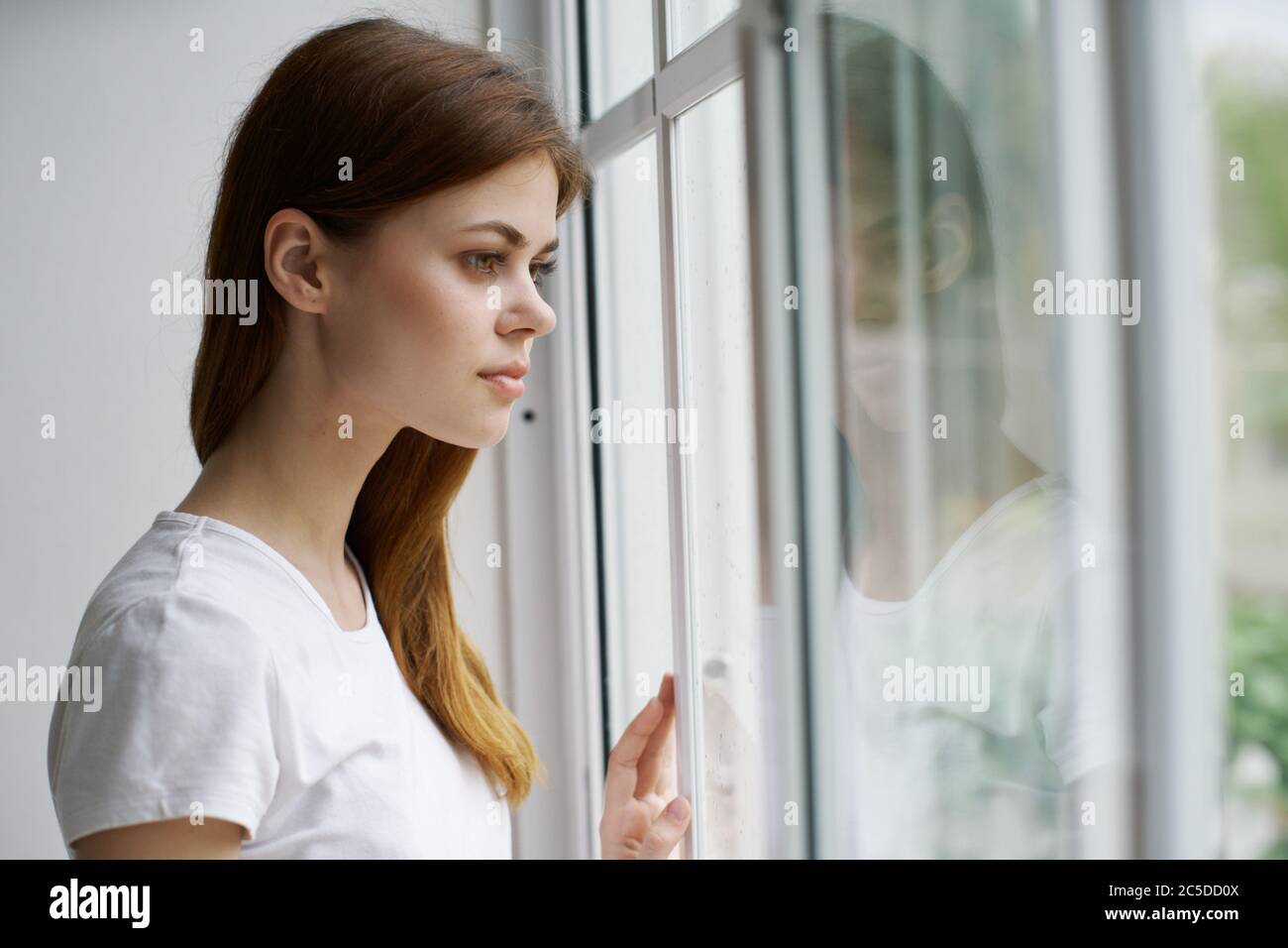 Side view of a pretty young woman looking out the window Stock Photo ...