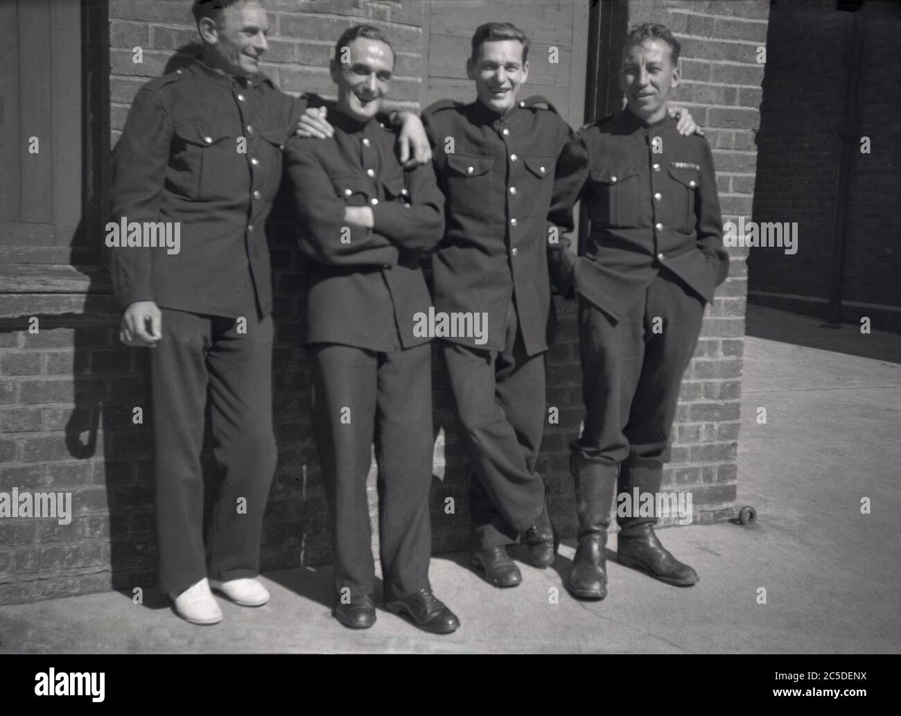 circa 1930s, four firemen in their uniform standing for a photo outside ...