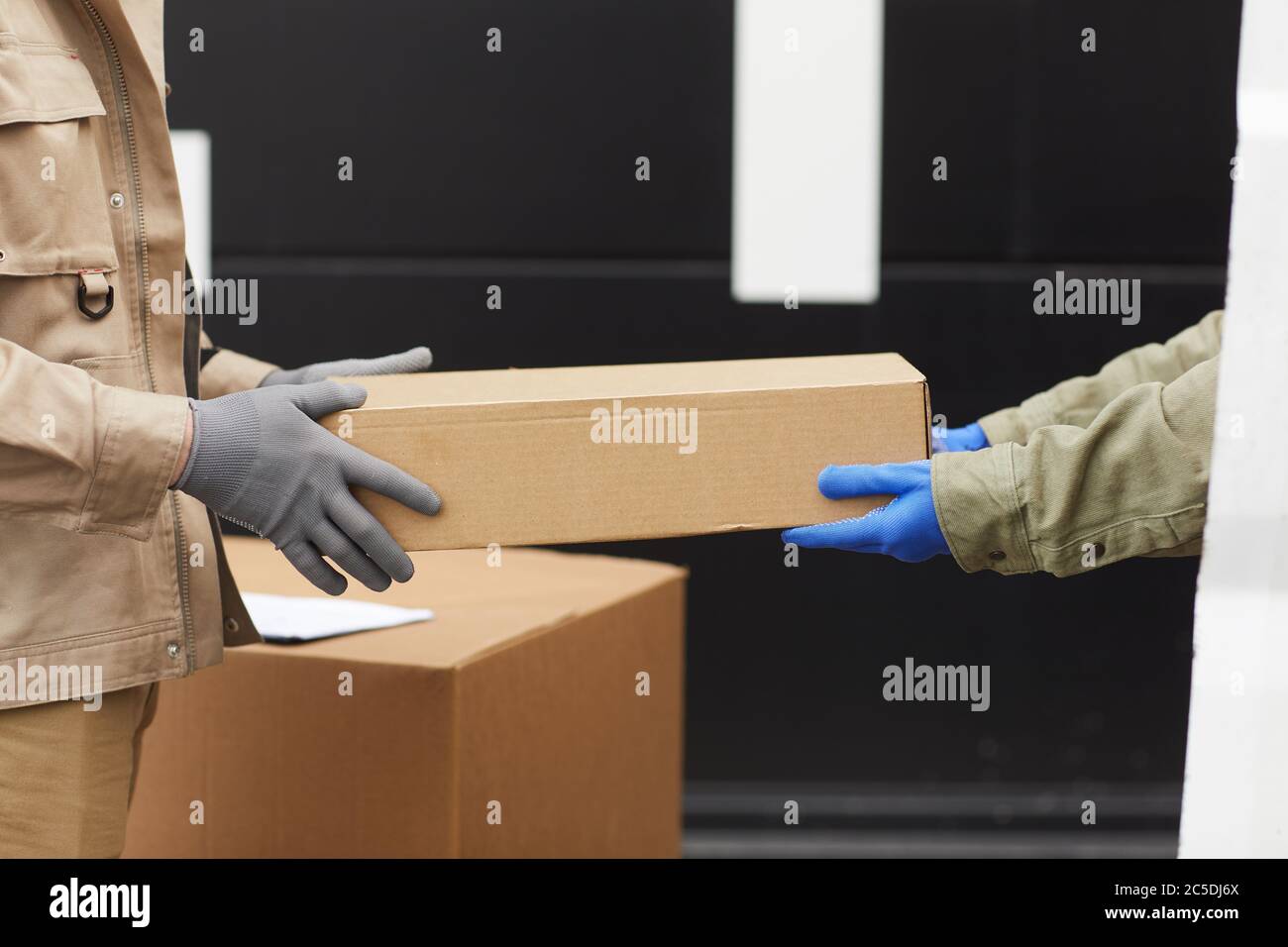 Close-up of manual workers in gloves passing the box to each other they ...