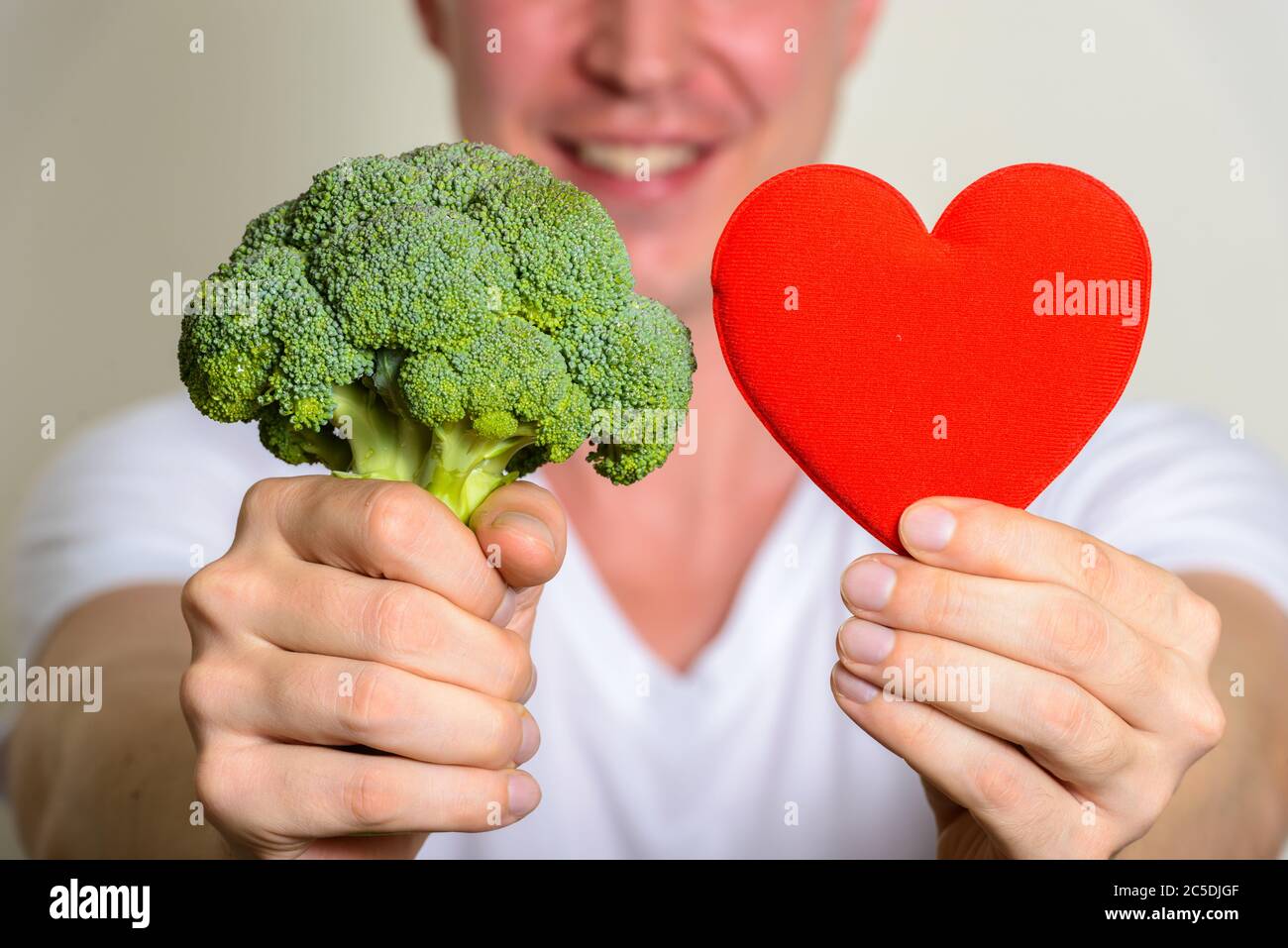 Face of happy young man giving broccoli and heart Stock Photo - Alamy