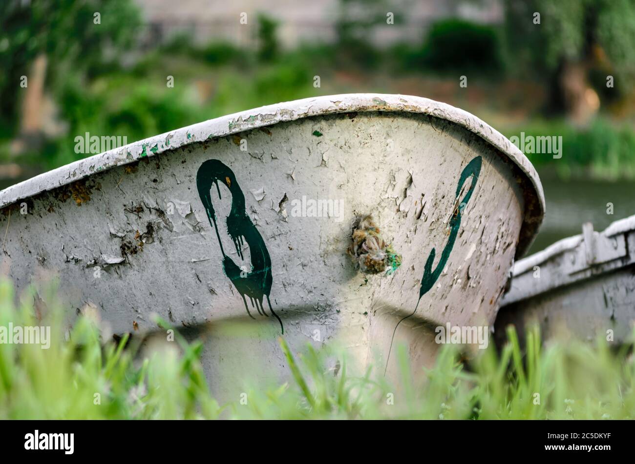 old boat number three on the river bank on green grass without people ...