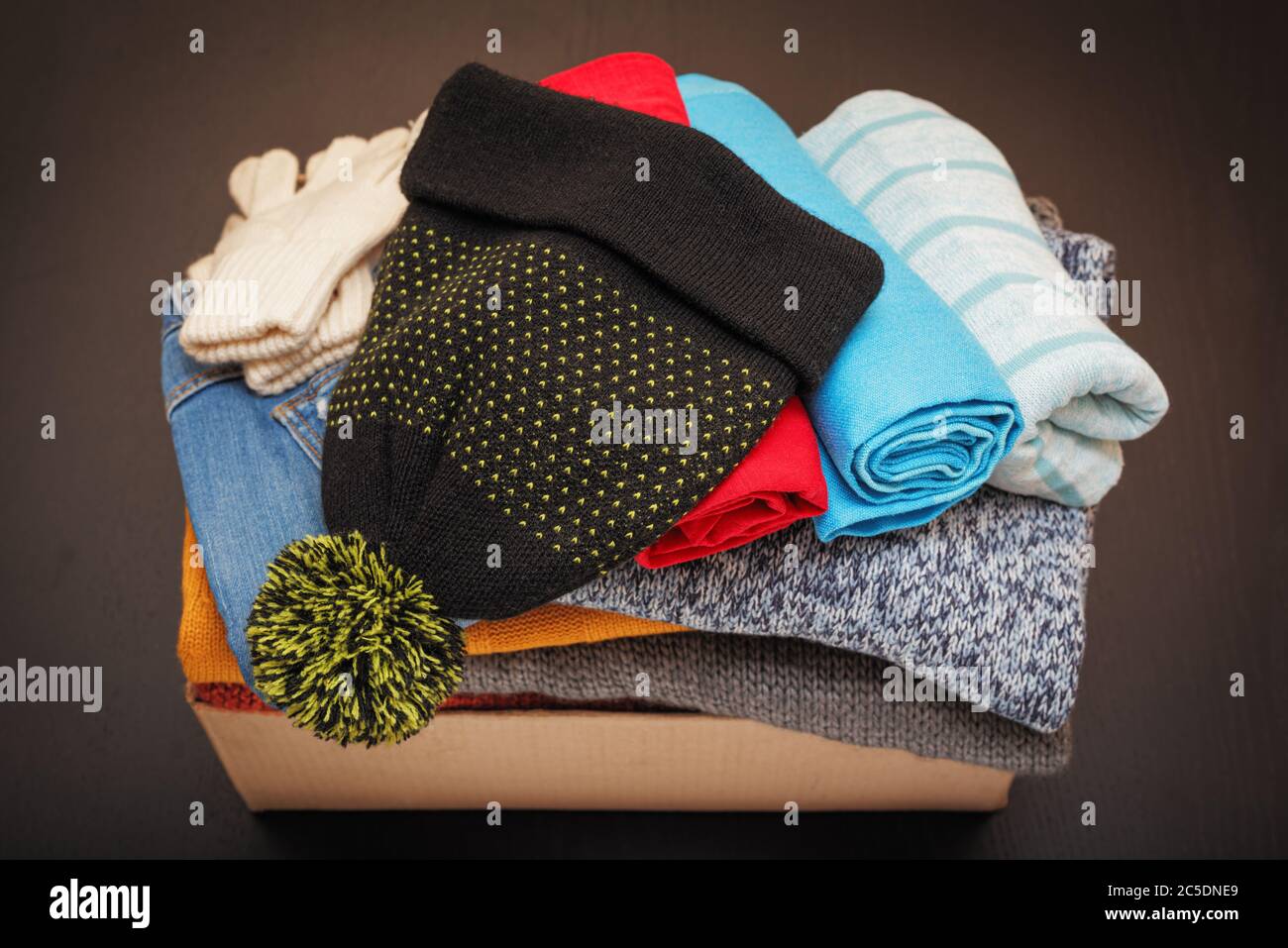 Donation box full of clothing on dark background. Closeup. View from ...
