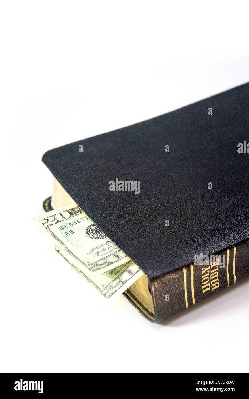 A holy Christian bible with a twenty dollar bill isolated on a white ...