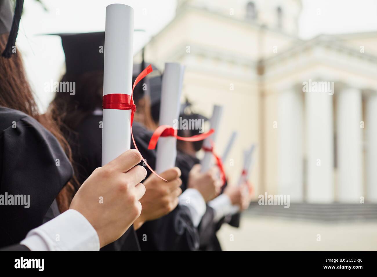 Graduates with diplomas in front of the university Stock Photo - Alamy