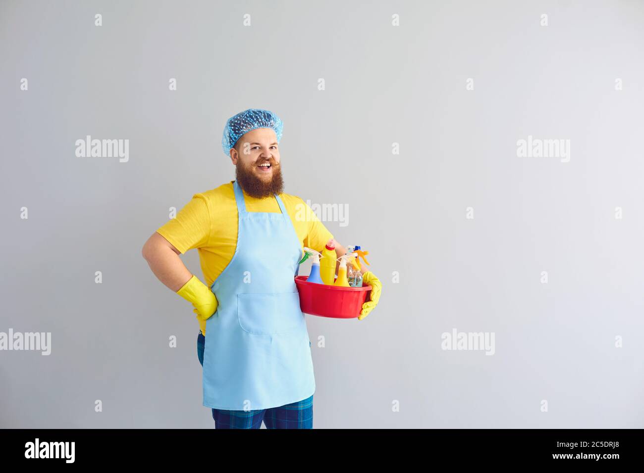 Funny fat guy with cleaning supplies on grey background, copy space ...
