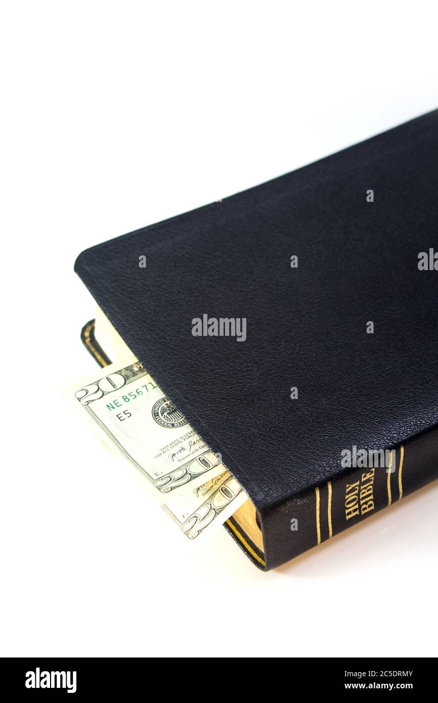 A holy Christian bible with a twenty dollar bill isolated on a white ...