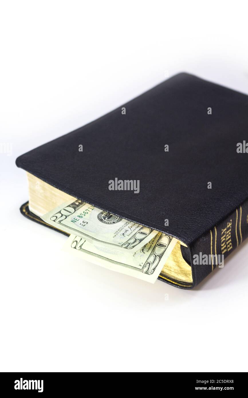 A holy Christian bible with a twenty dollar bill isolated on a white ...