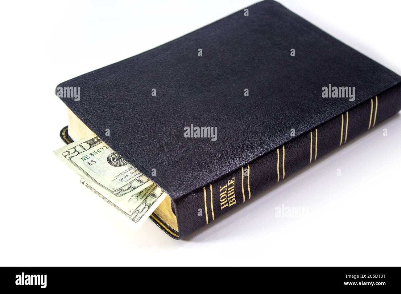 A holy Christian bible with a twenty dollar bill isolated on a white ...