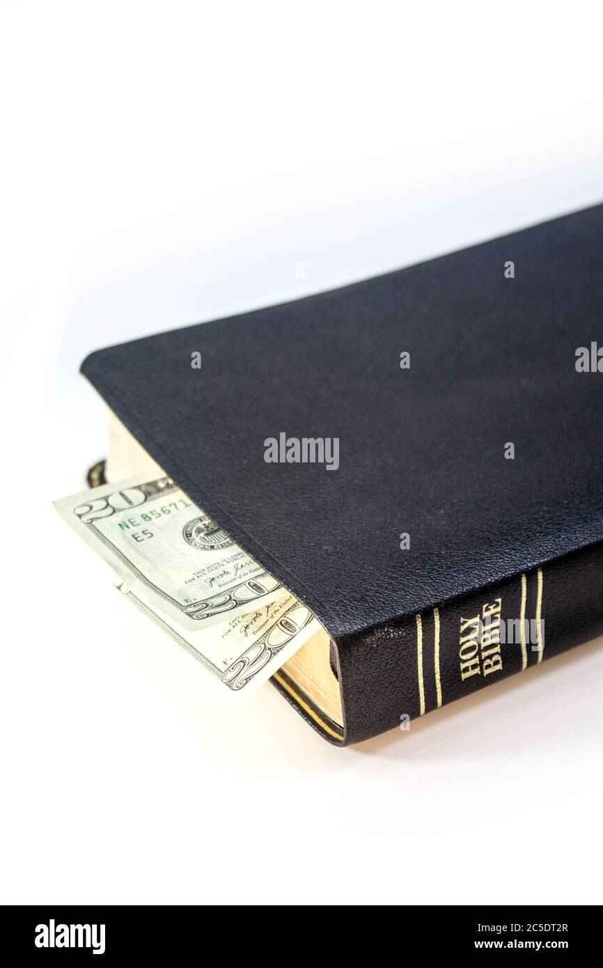A holy Christian bible with a twenty dollar bill isolated on a white ...
