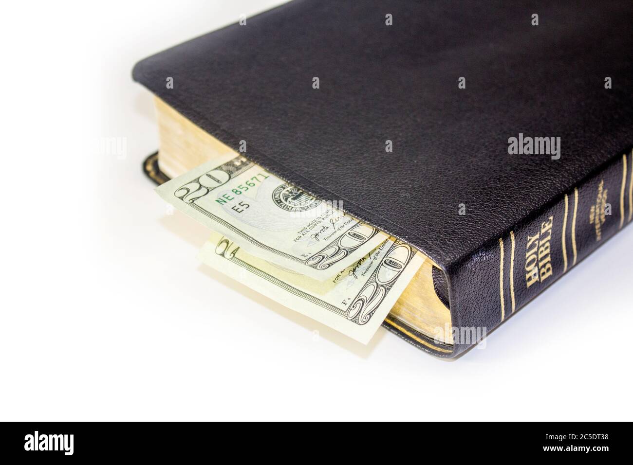 A holy Christian bible with a twenty dollar bill isolated on a white ...