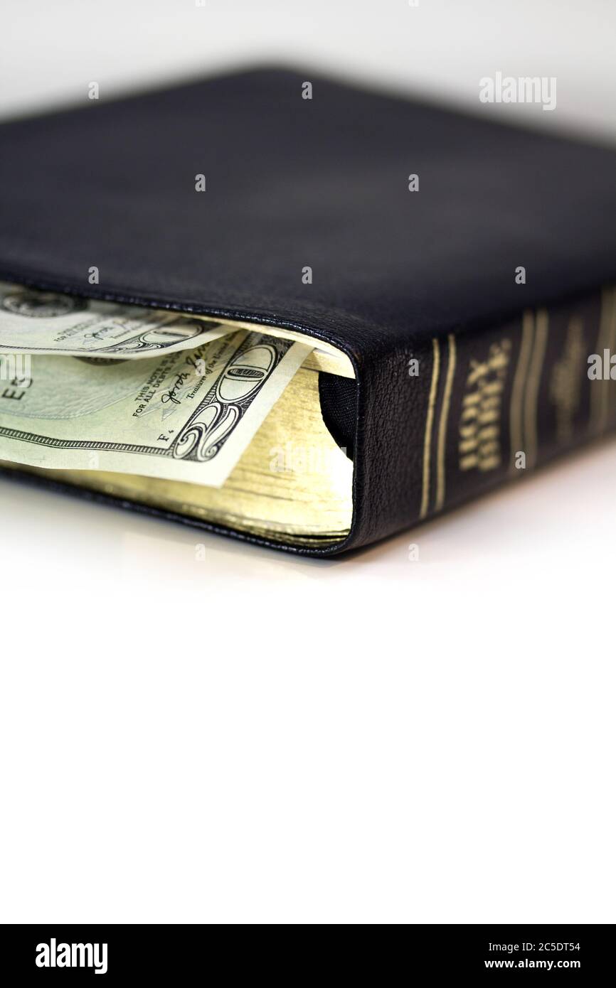 A holy Christian bible with a twenty dollar bill isolated on a white ...