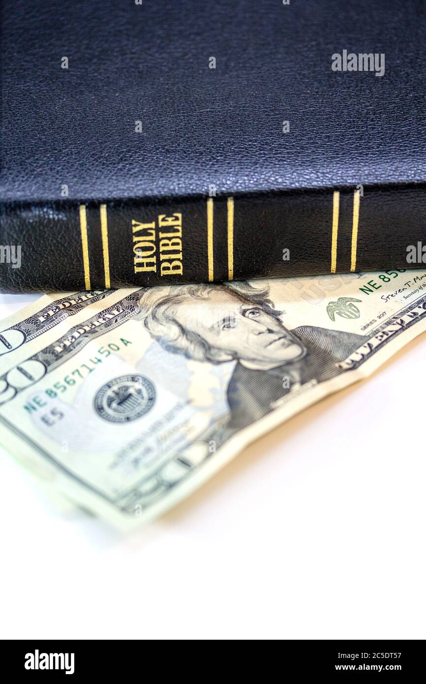 A holy Christian bible with a twenty dollar bill isolated on a white ...