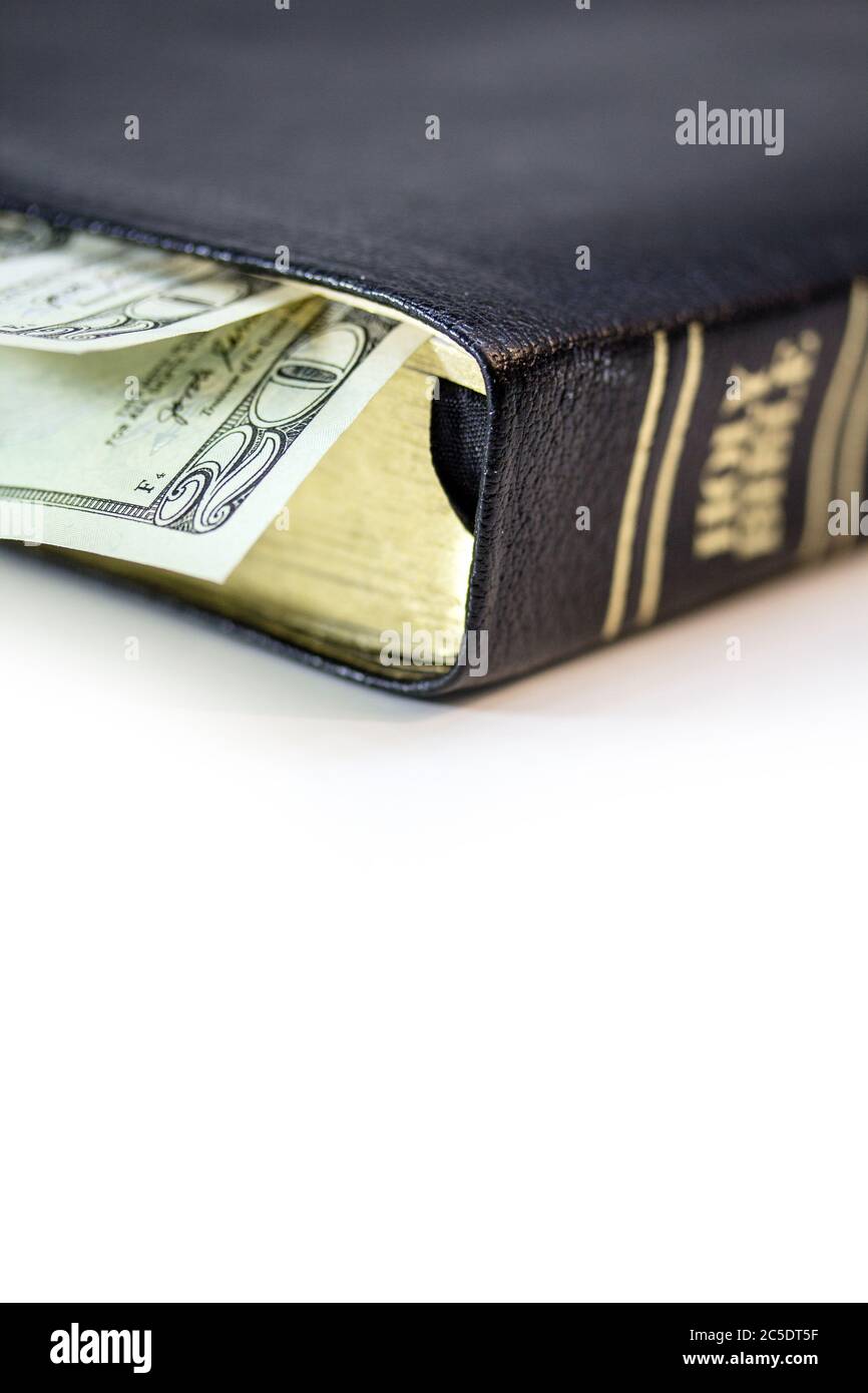A holy Christian bible with a twenty dollar bill isolated on a white ...