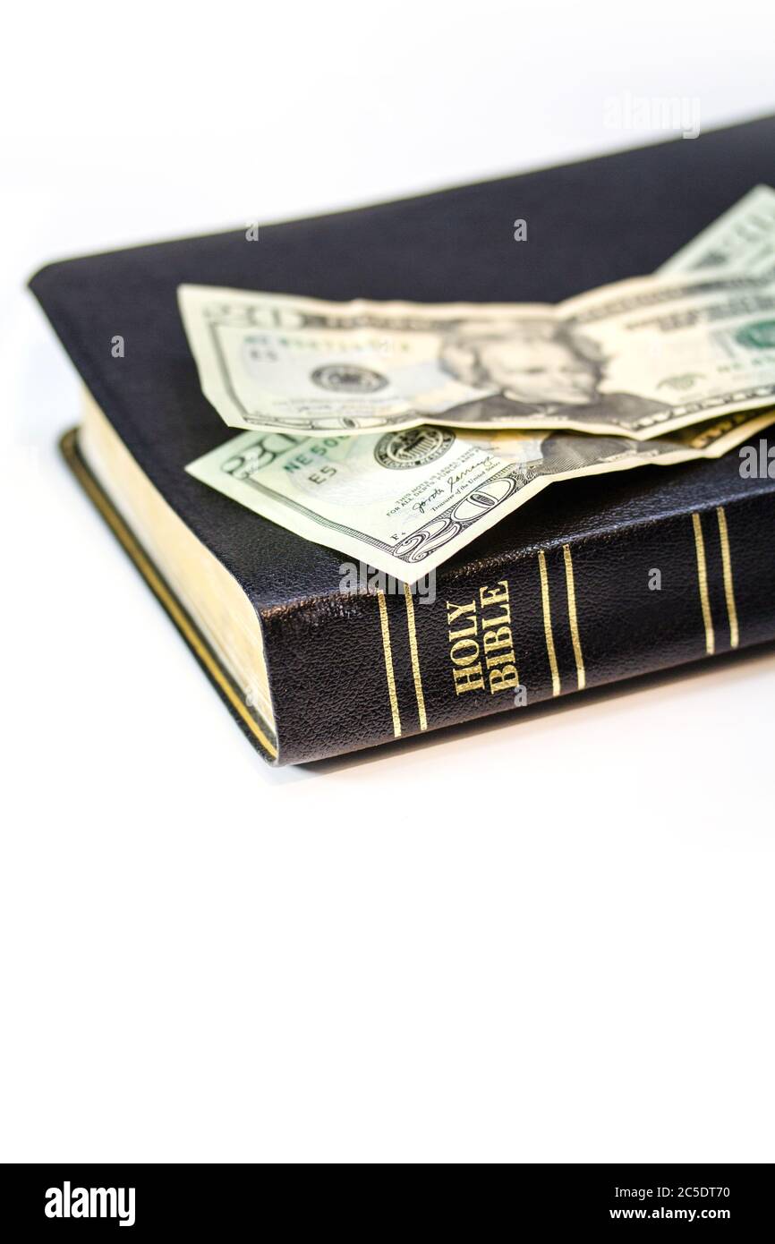 A holy Christian bible with a twenty dollar bill isolated on a white ...