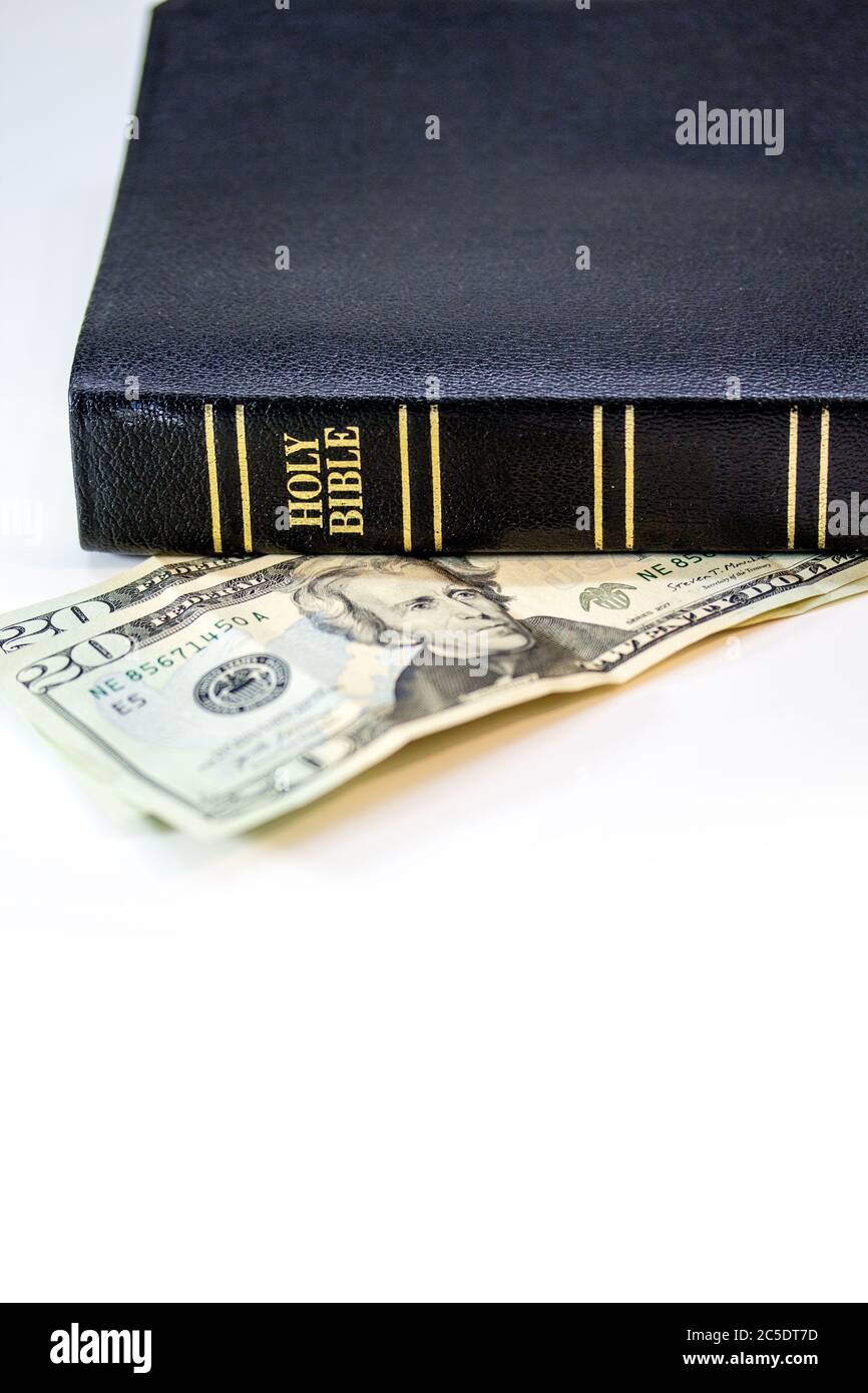 A holy Christian bible with a twenty dollar bill isolated on a white ...