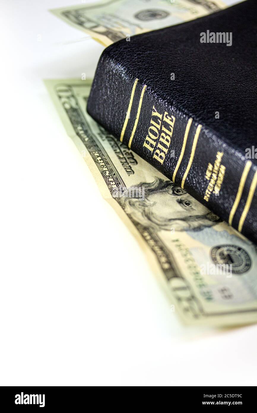 A holy Christian bible with a twenty dollar bill isolated on a white ...