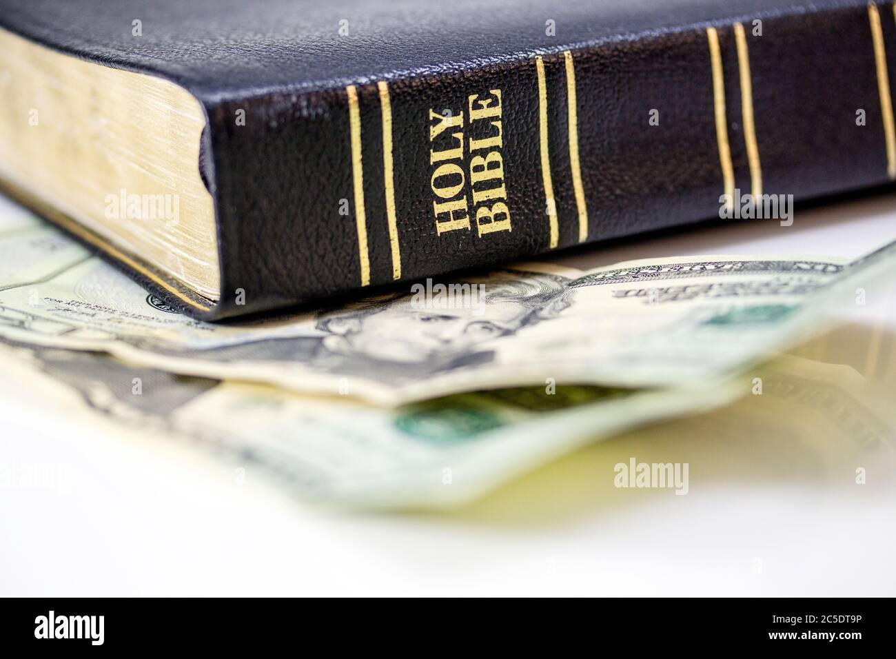A holy Christian bible with a twenty dollar bill isolated on a white ...