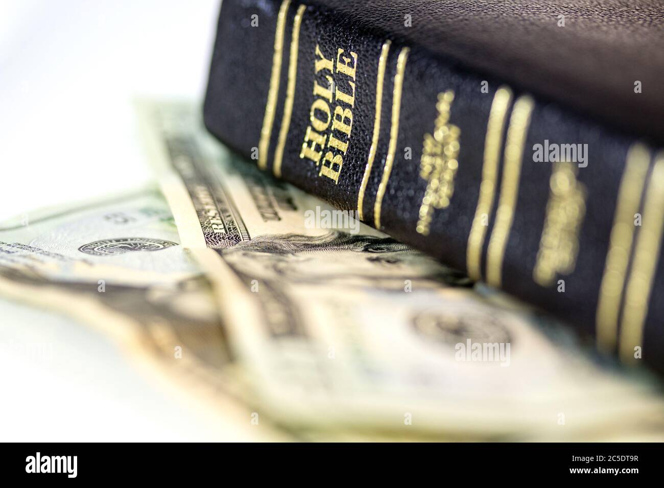 A holy Christian bible with a twenty dollar bill isolated on a white ...