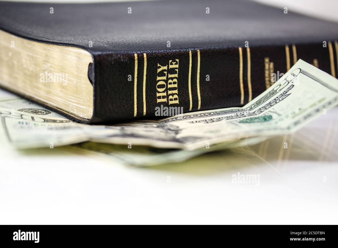 A holy Christian bible with a twenty dollar bill isolated on a white ...