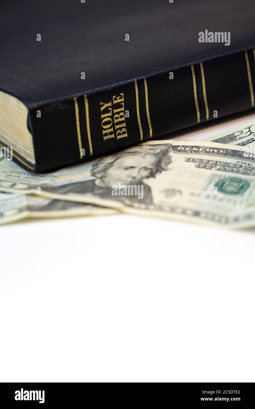 A holy Christian bible with a twenty dollar bill isolated on a white ...