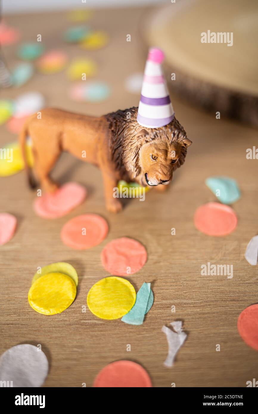 Plastic lion toy with party hat on a colorful spots wooden table Stock ...