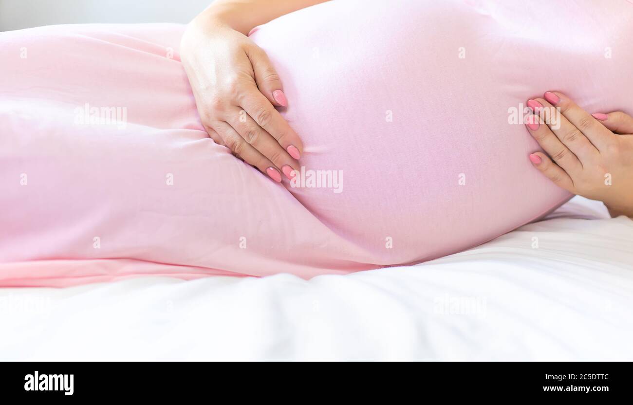 A pregnant woman in bed hugs her stomach. Selective focus. people Stock ...