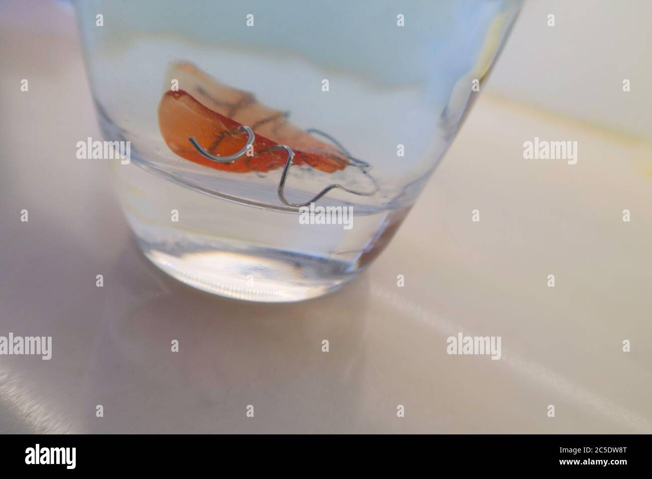 Hawley bow orthodontic teeth retainer in glass of denture cleanser ...