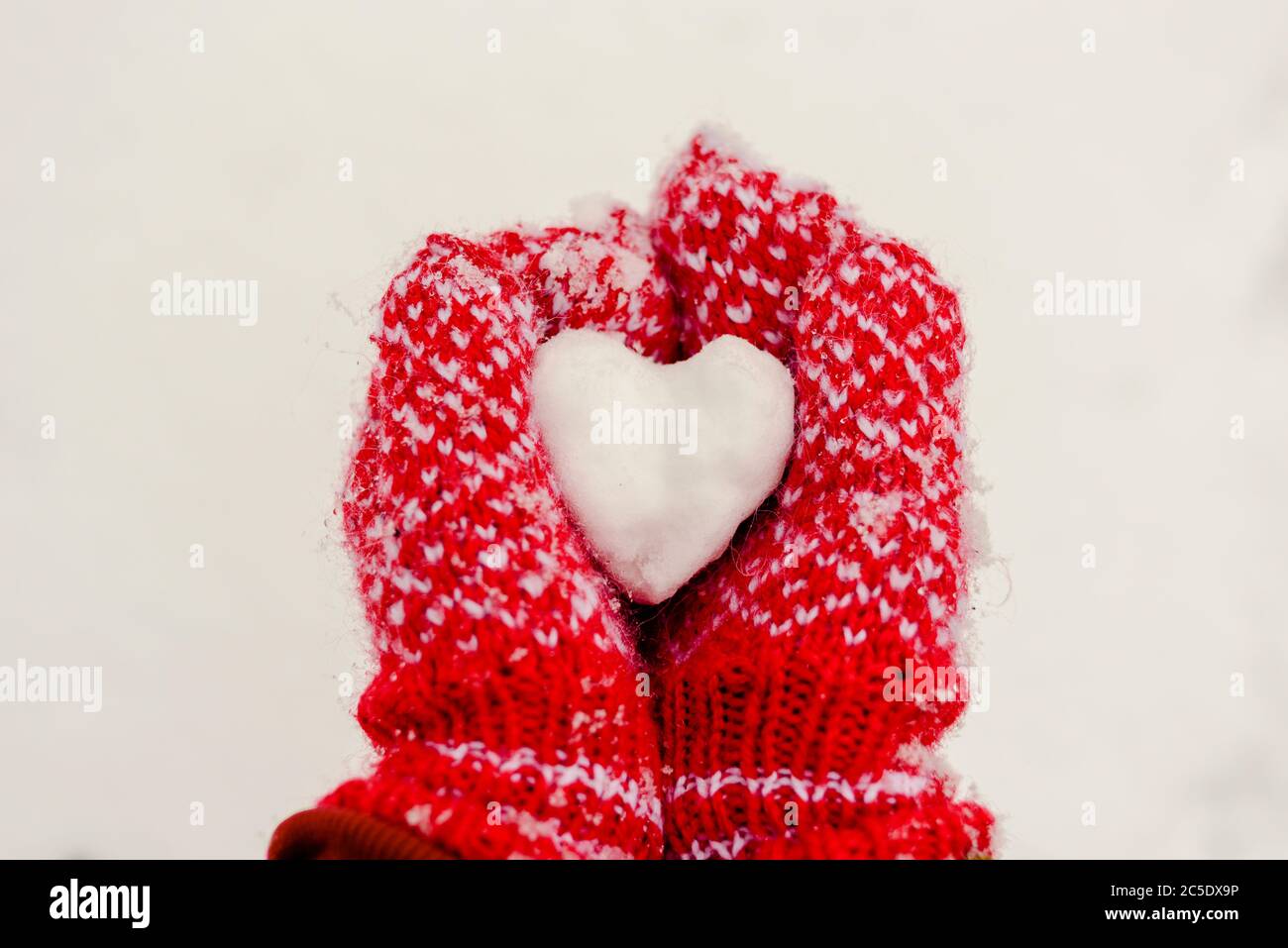 Heart shaped snowball in hands in red knitted mittens Stock Photo - Alamy