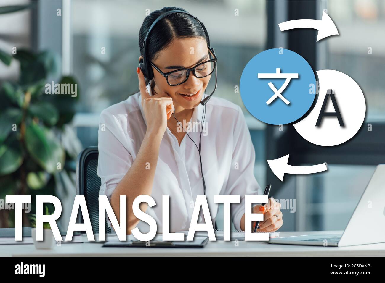 smiling asian translator working online with headset and laptop in ...