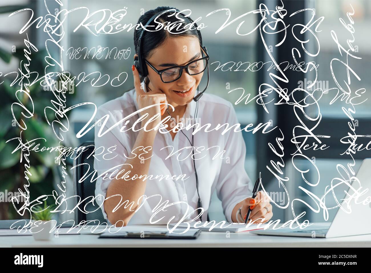 smiling asian translator working online with headset and laptop in ...