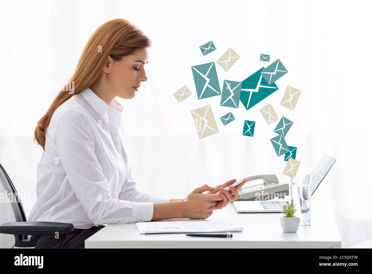 Side view of businesswoman using smartphone near documents and laptop ...