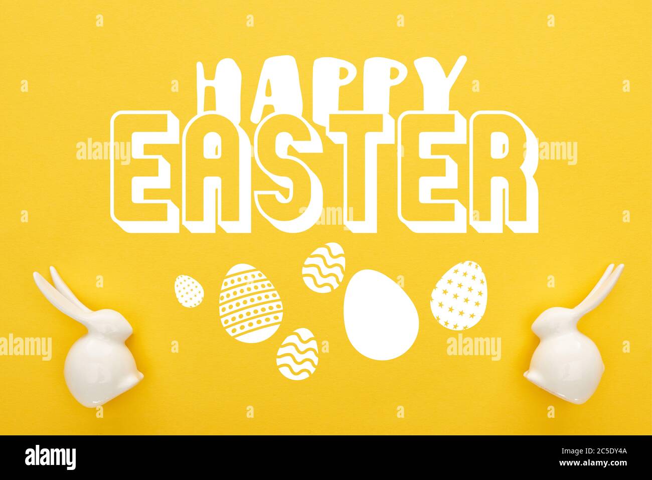 top view of white Easter bunnies on colorful yellow background with ...