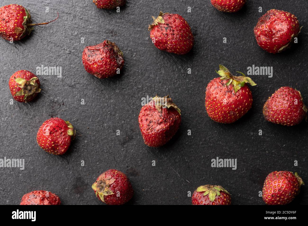 the spoiled strawberry berry is beautifully laid out on a textured ...