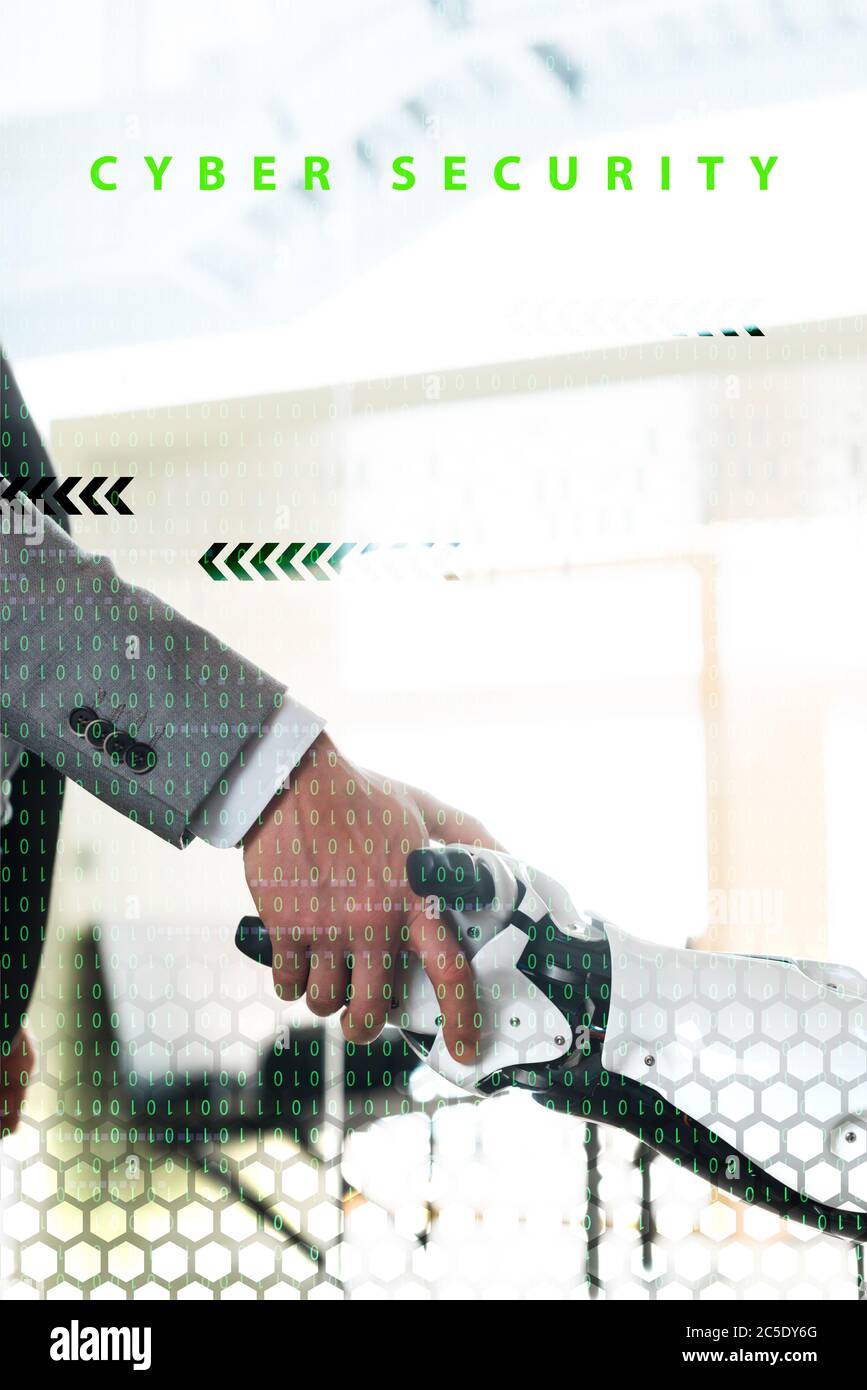 partial view of businessman and robot shaking hands in office, cyber ...