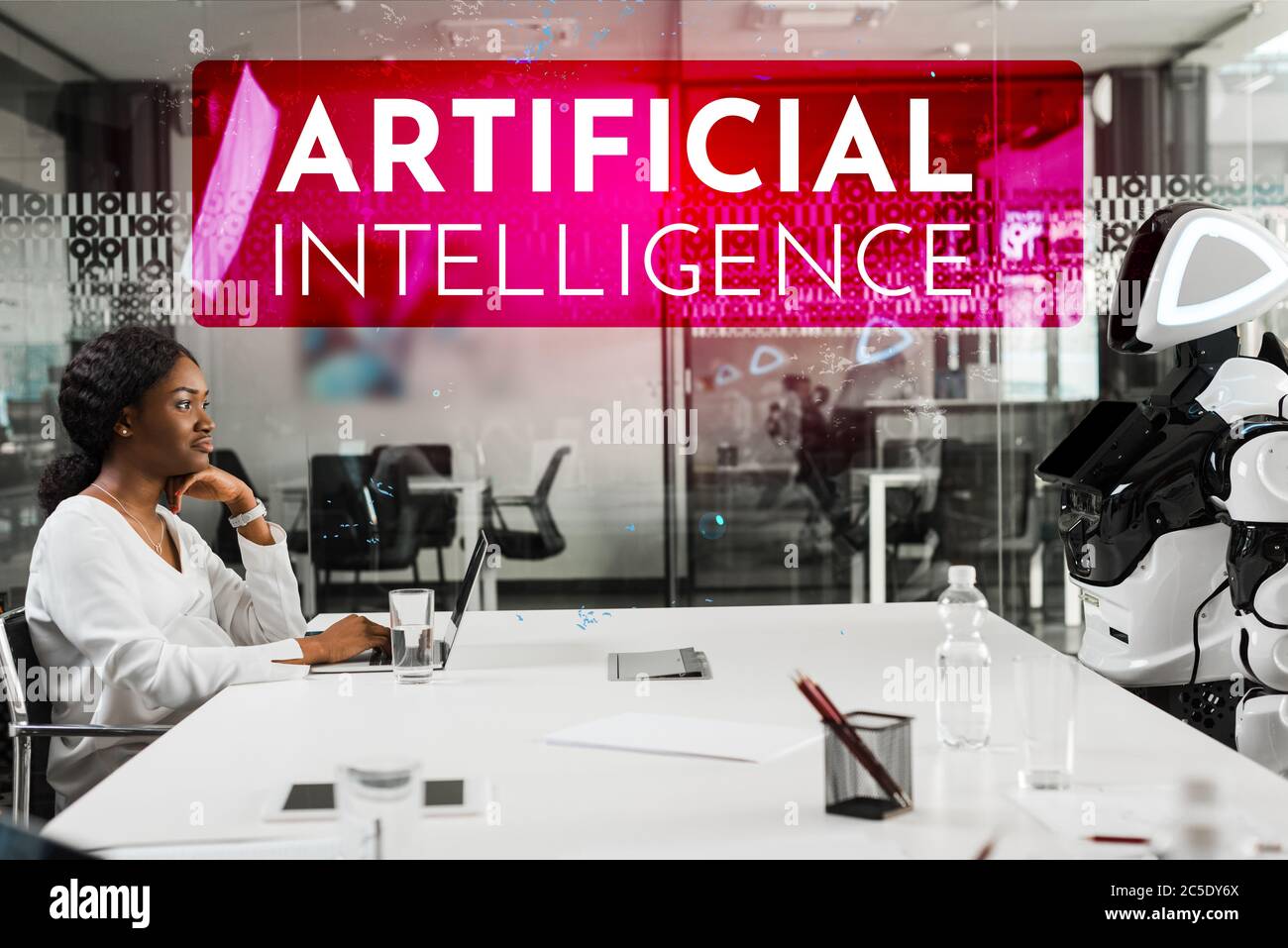 smiling african american businesswoman and robot sitting at desk in ...