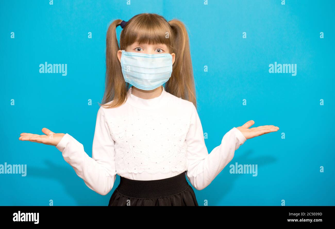 Portrait of shrugging confused child girl in medical mask showing ...