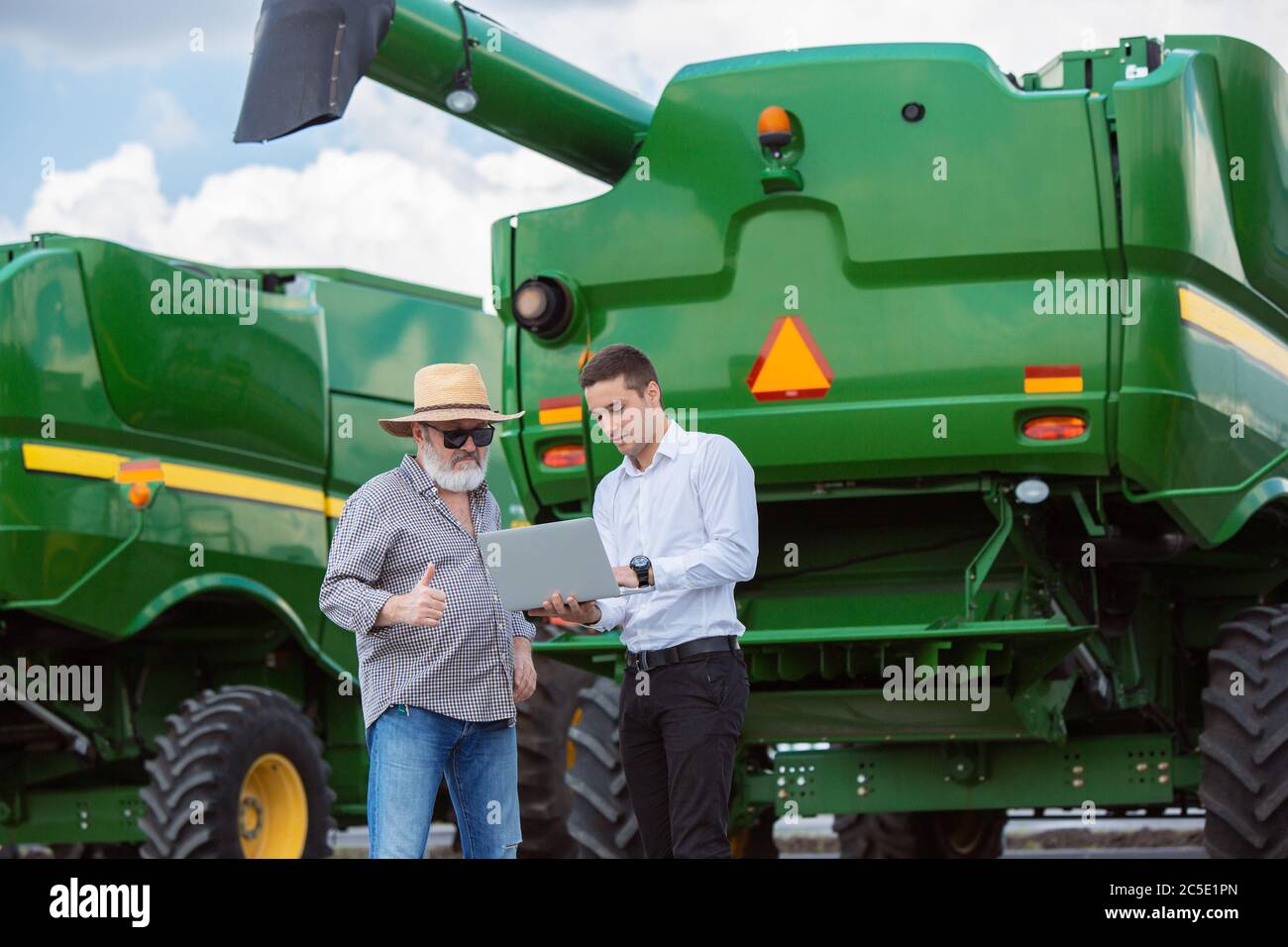 Professional farmer with a modern combine at field in sunlight at work ...